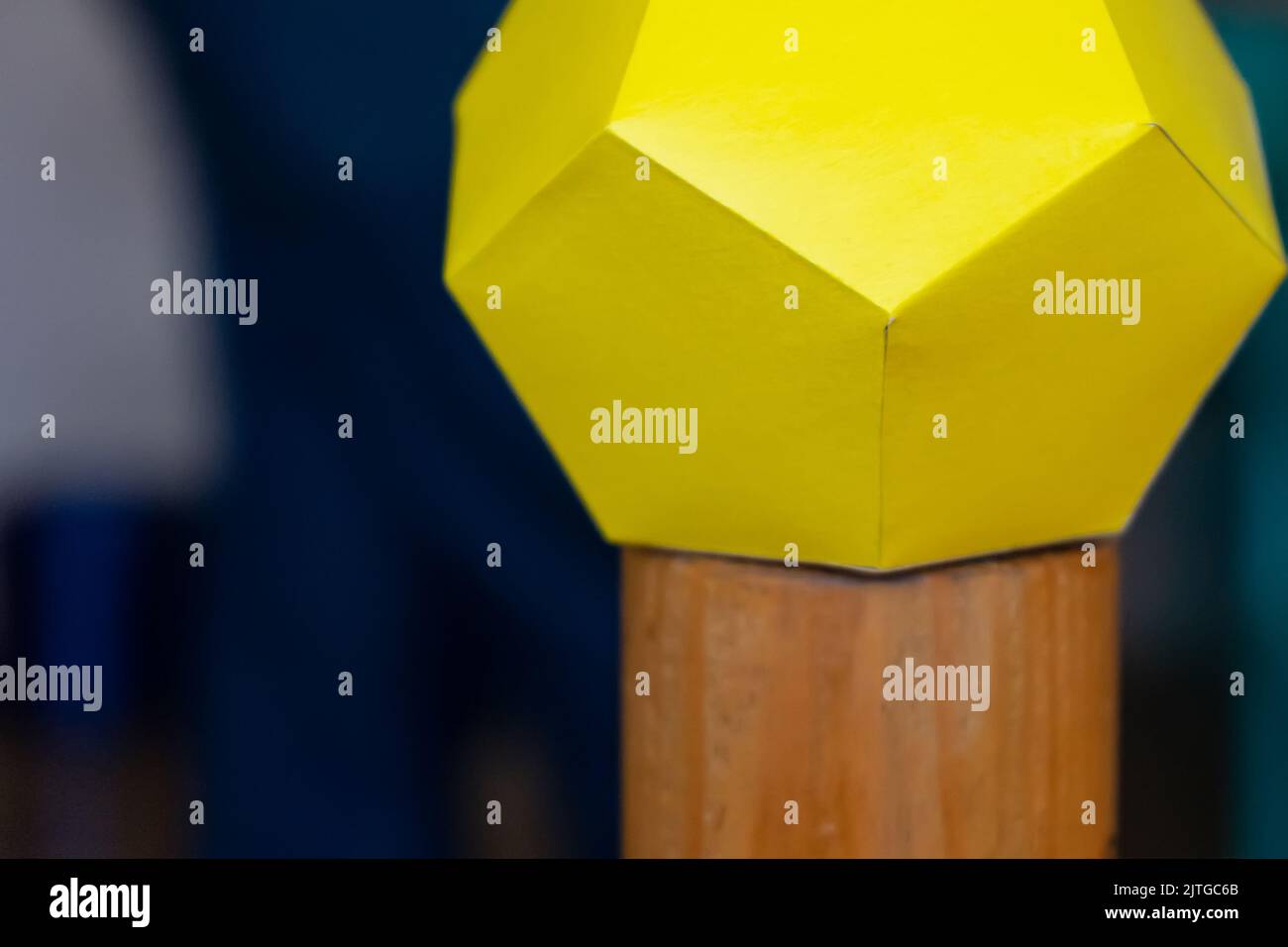 The multifaceted yellow figure is made of many yellow paper pentagons ...
