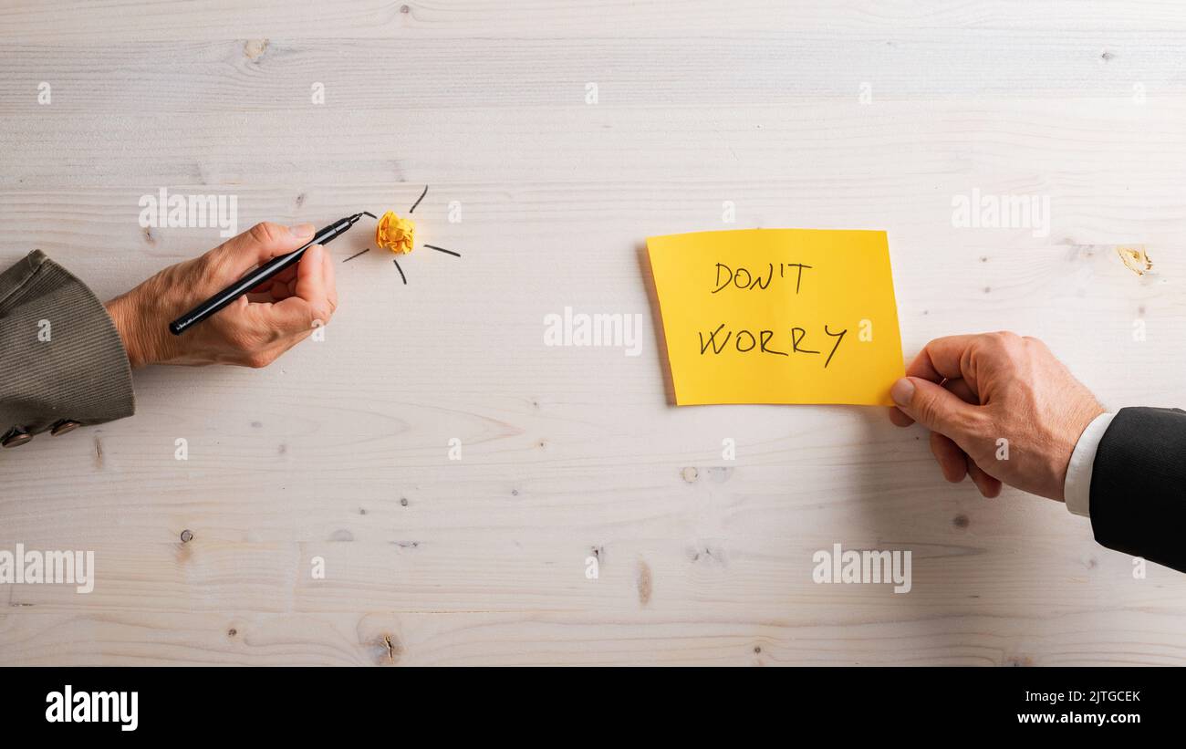 Male hand placing a yellow paper with Dont worry sign on it over white ...