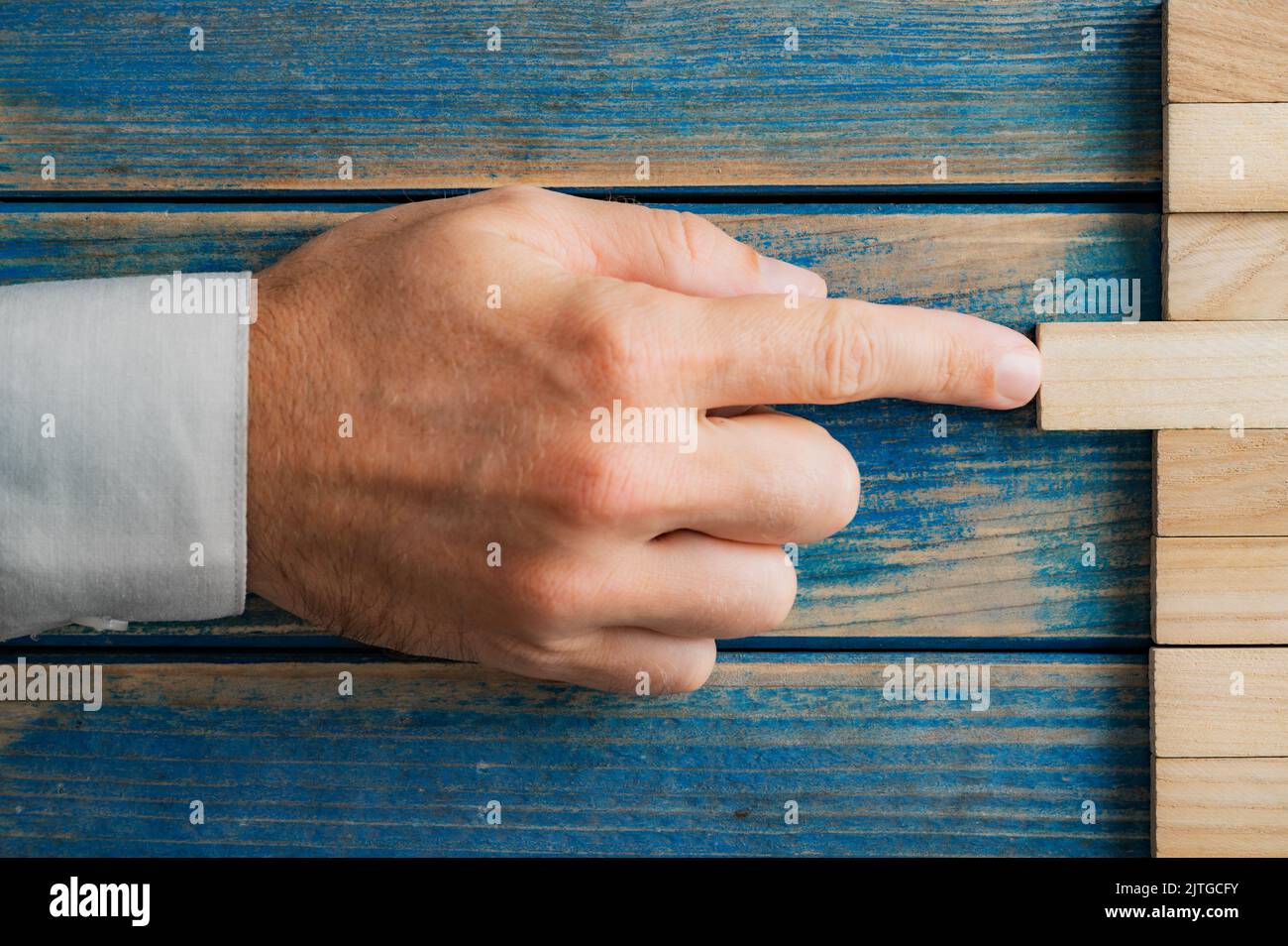 Hand of caucasian businessman pushing a wooden peg into a stack of them ...