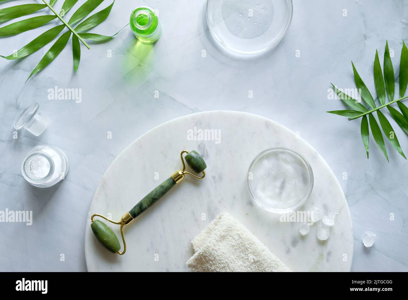 Home made moisturizer and green jade stone face roller on off white ...