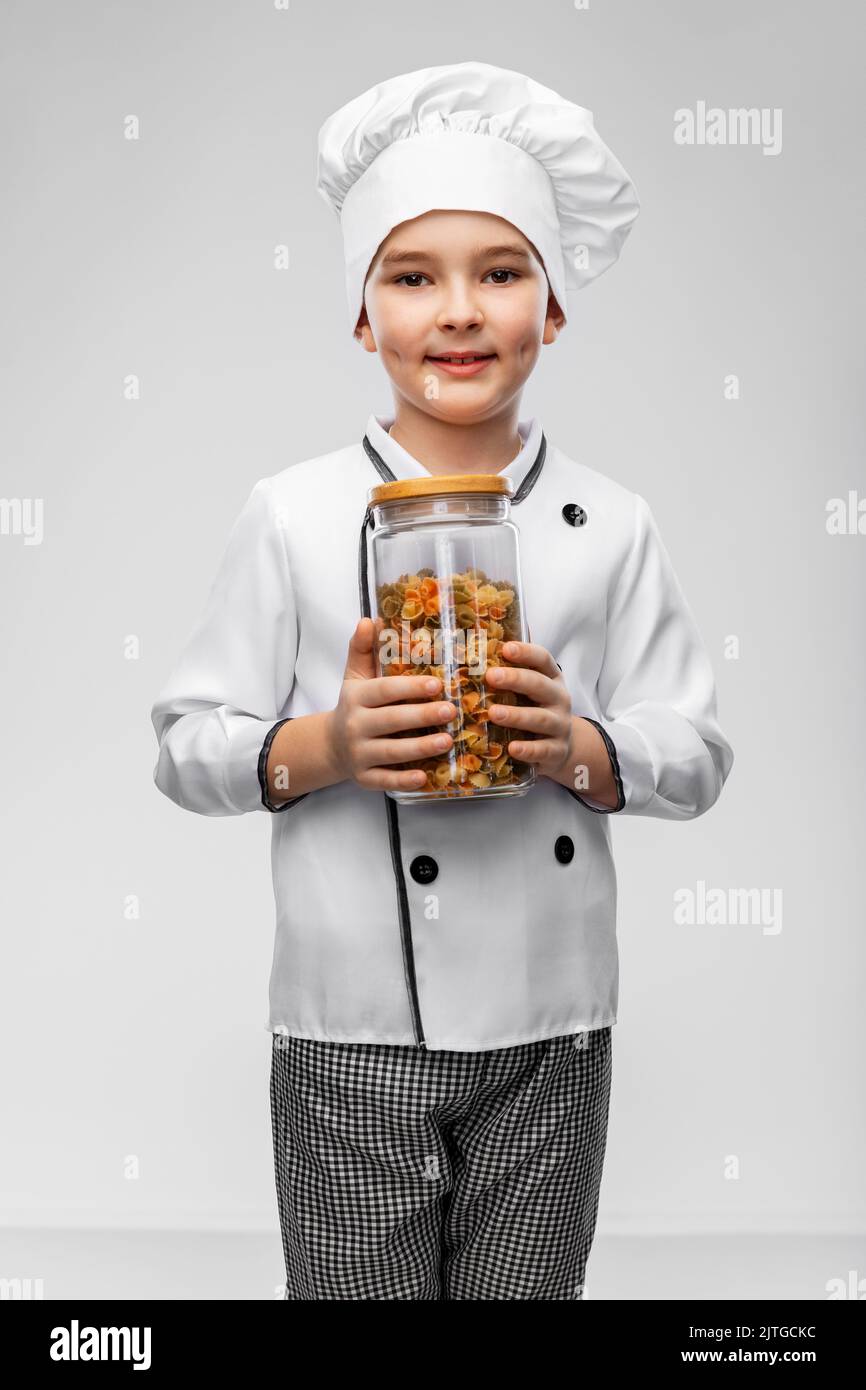 smiling boy in chef's toque holding jar with pasta Stock Photo - Alamy