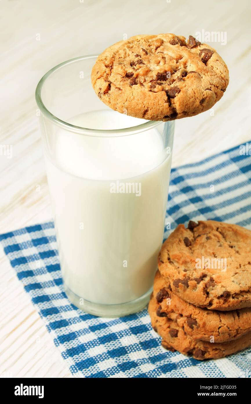 Chocolate cookie and glass of milk on blue napkin on white wooden table ...