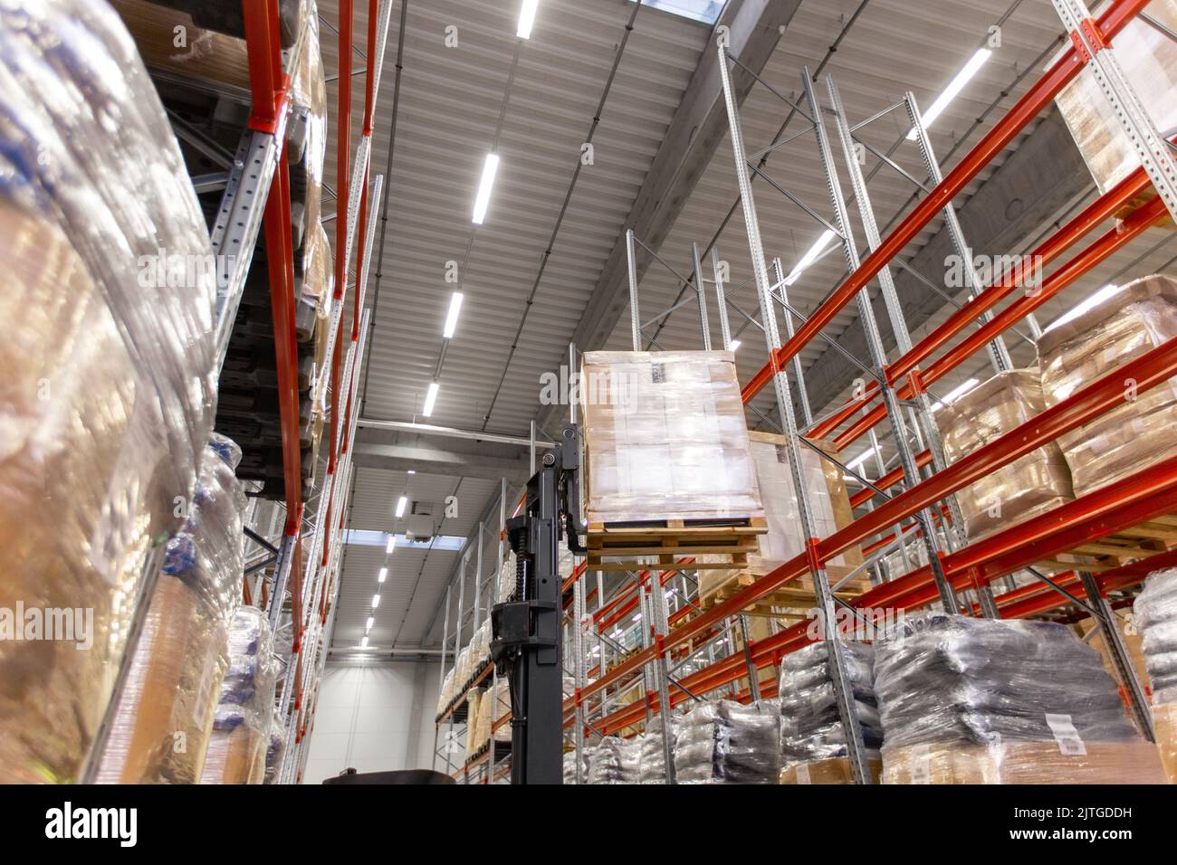 forklift loader loading cargo to warehouse shelves Stock Photo - Alamy