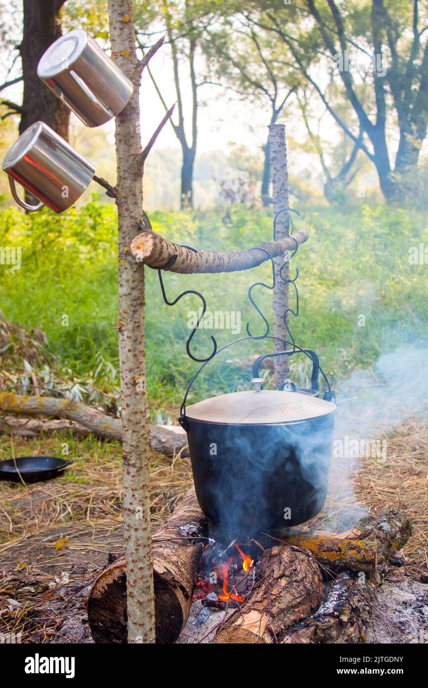 smoked tourist pot over camp fire. Process of cooking on the nature ...