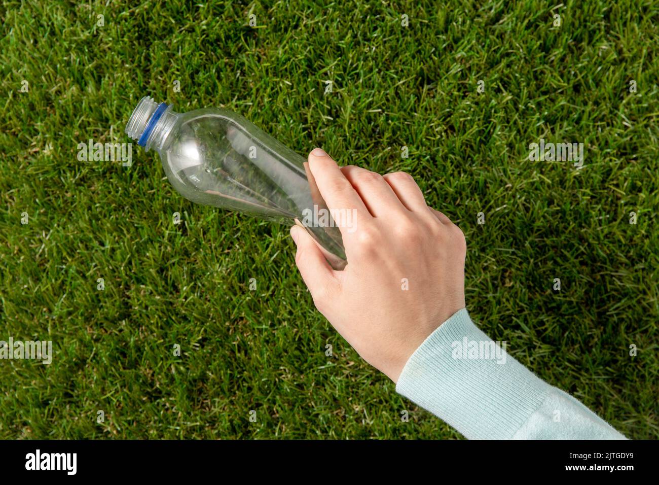 hand removing plastic bottle from grass Stock Photo - Alamy