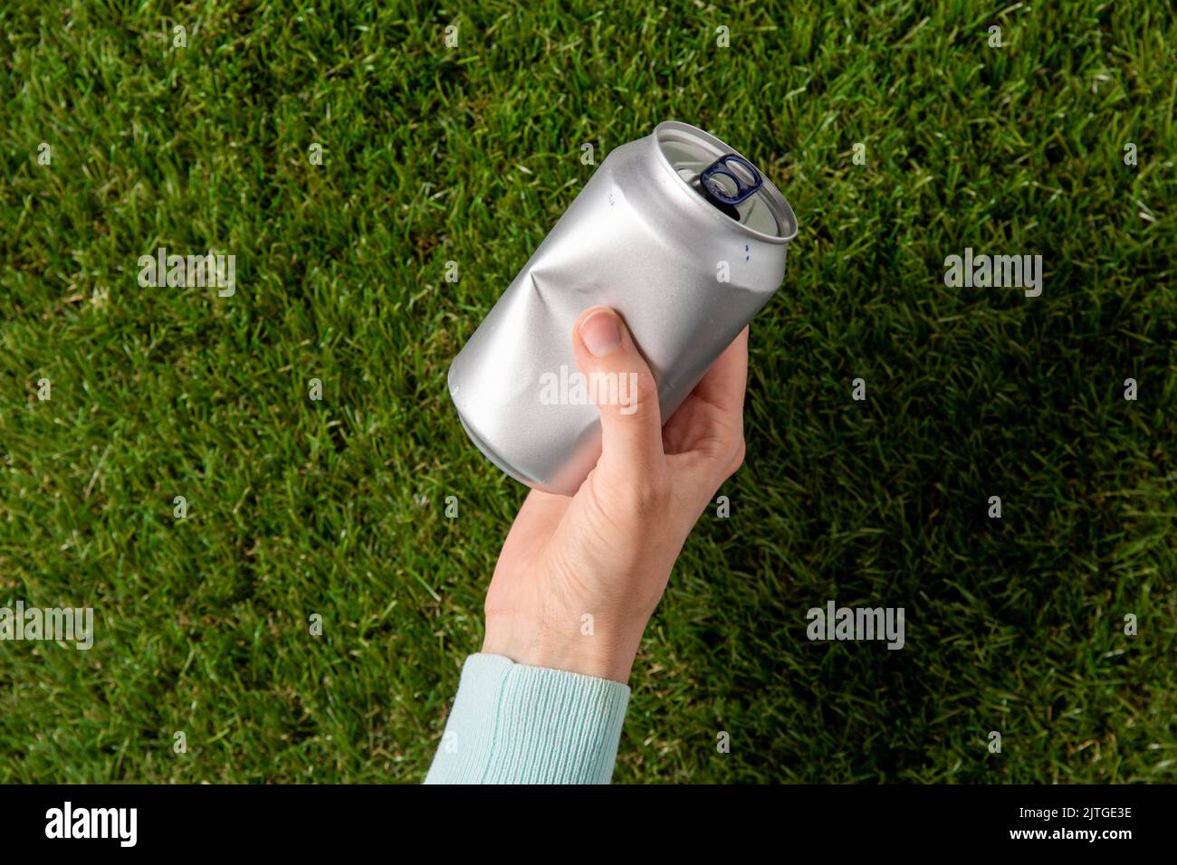 close up of hand removing used tin can from grass Stock Photo - Alamy