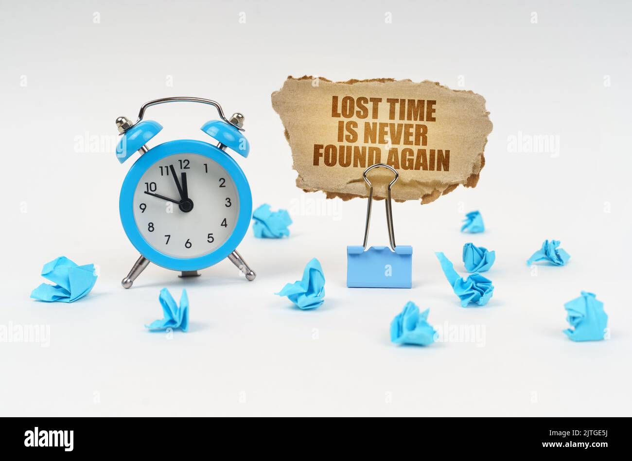 Time concept. On a white surface, an alarm clock, an office clip ...