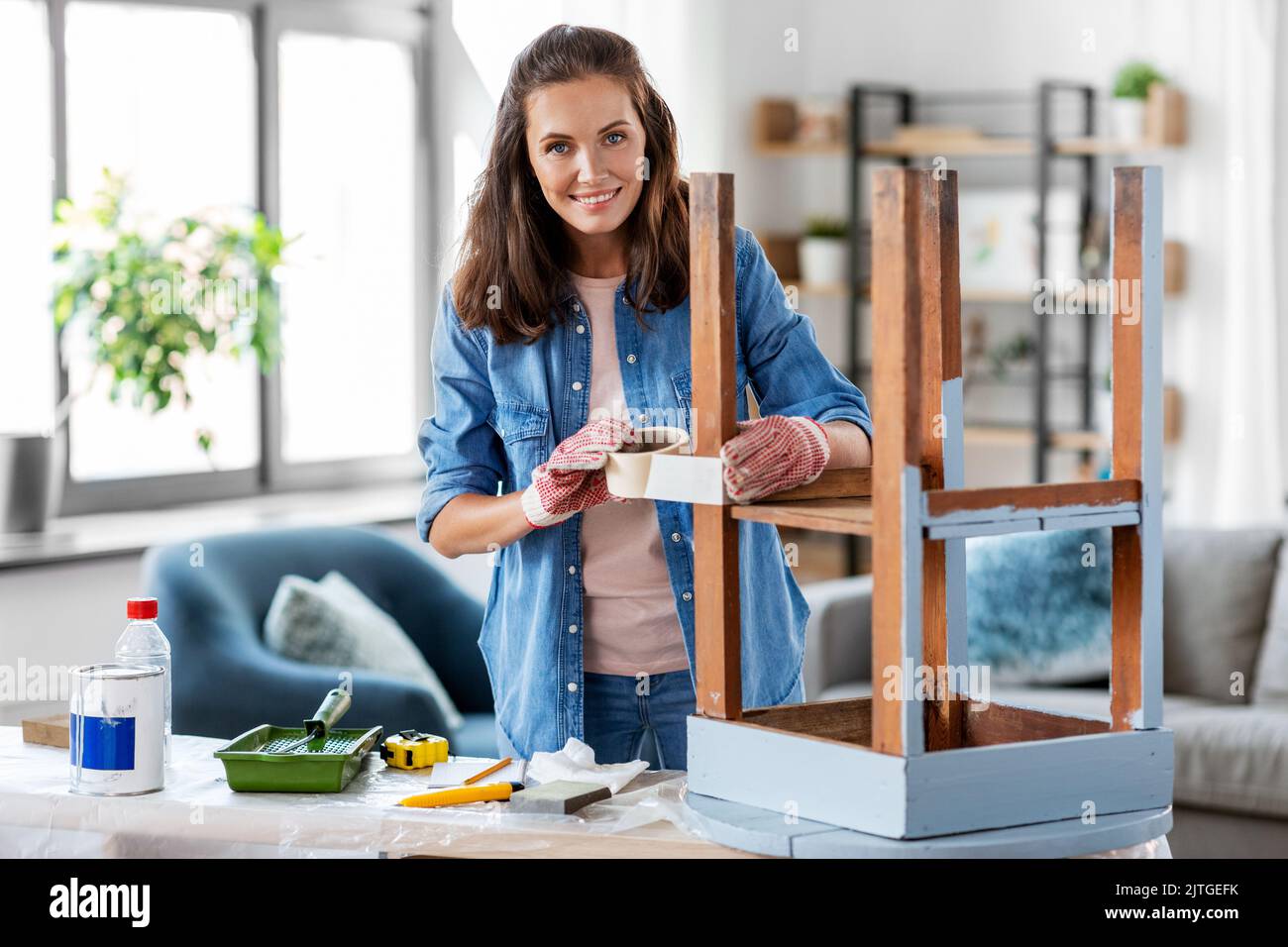 woman sticking masking tape to table for repaint Stock Photo - Alamy