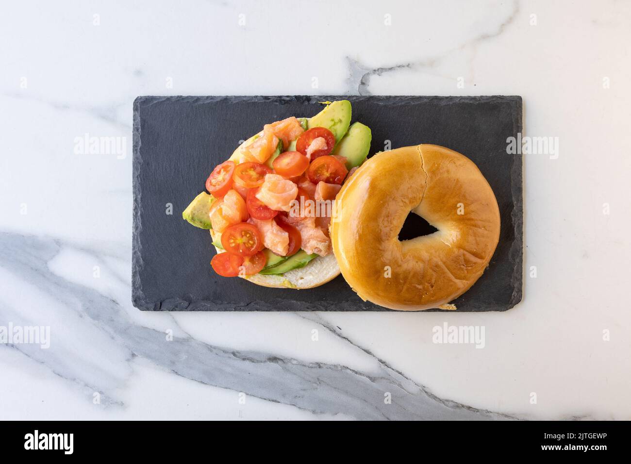 A top view of an open cut bagel with delicious tomatoes and avocados ...