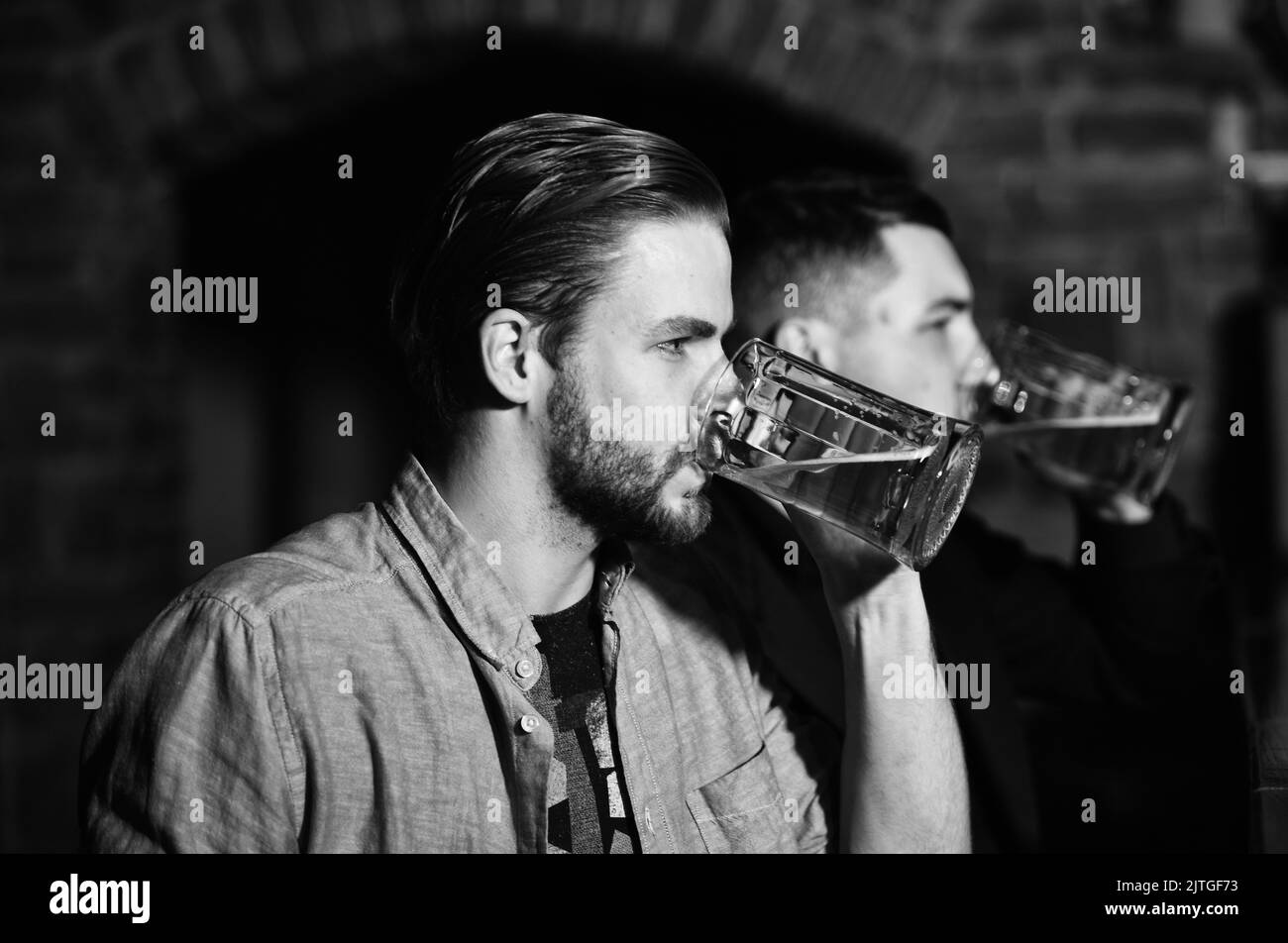 Guys with beards at wooden bar counter hold glasses of light beer. Men ...