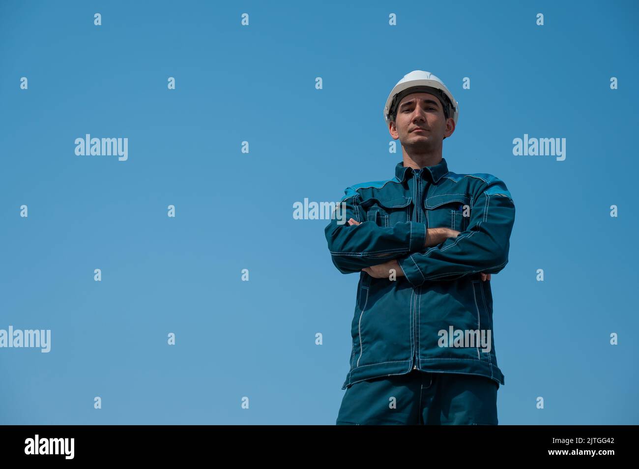 A caucasian man in work clothes and a construction helmet stands ...