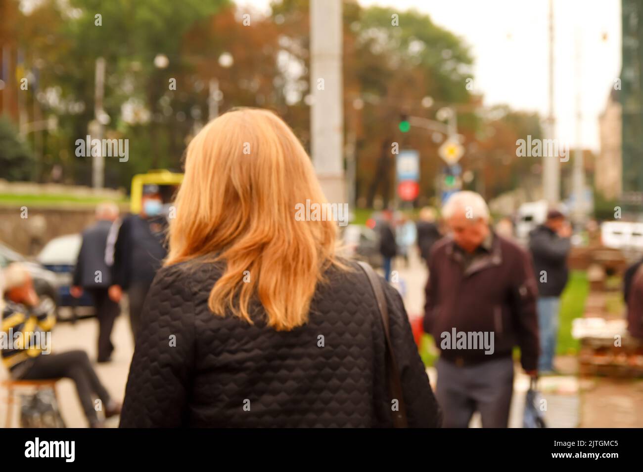 Defocus urban citizen concept. Rear view of blonde woman crossing ...