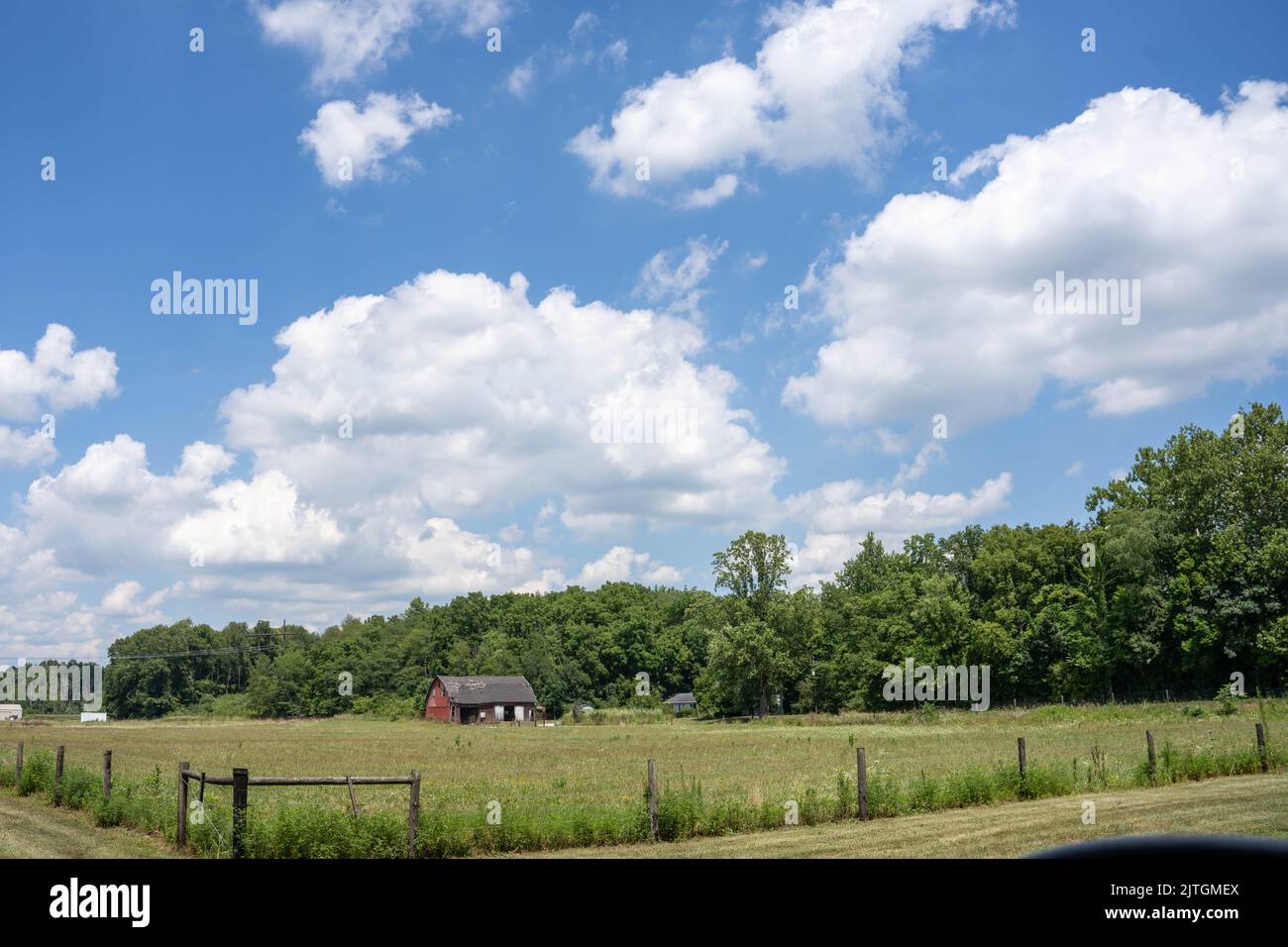 A scenic shot of a red barn house surrounded by beautiful greenery ...