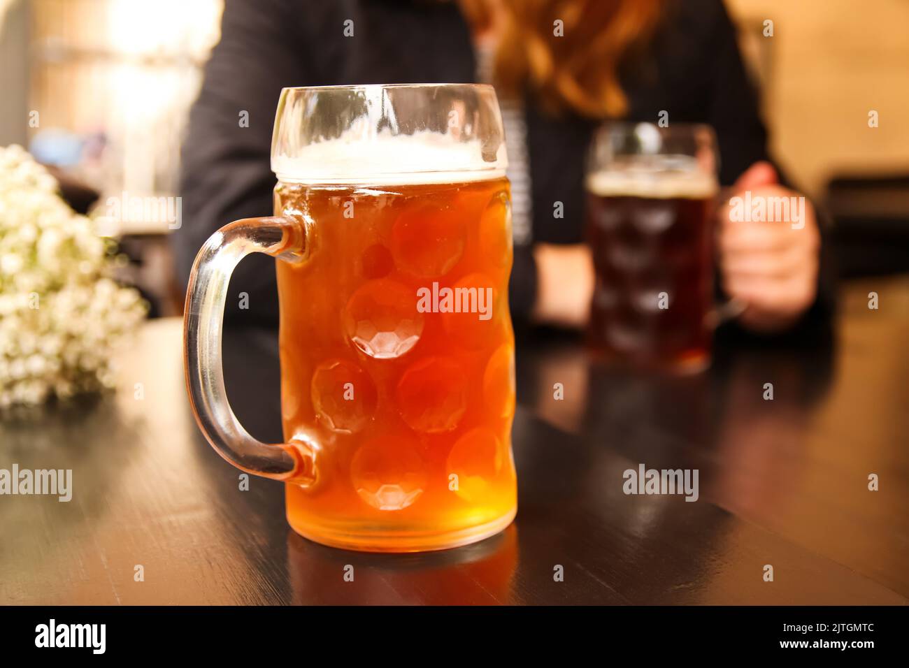 Defocus mug of light beer. Closeup of two hands clinking beer stein ...