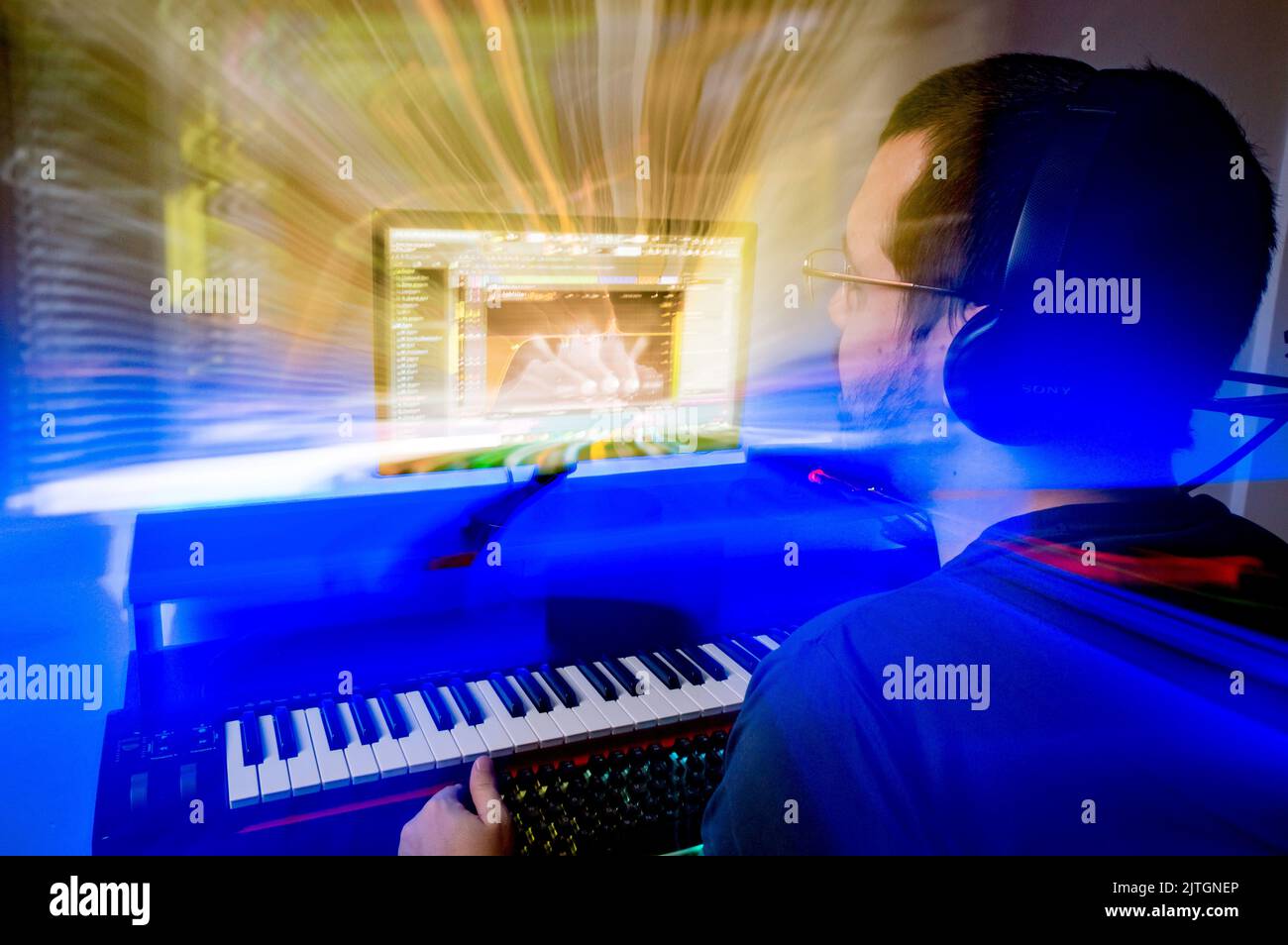 rear view of caucasian man with headphones and glasses sitting in his ...