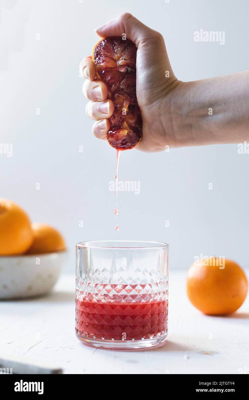 Squeezing fresh orange juice in to a glass Stock Photo - Alamy