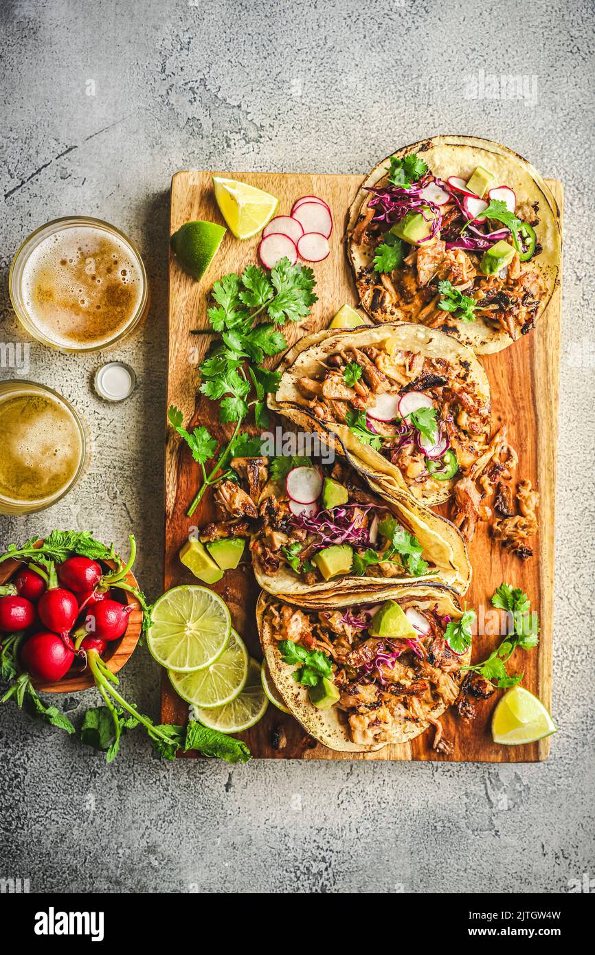 Assembled tacos with pulled pork, radish, lime and herb garnish on ...