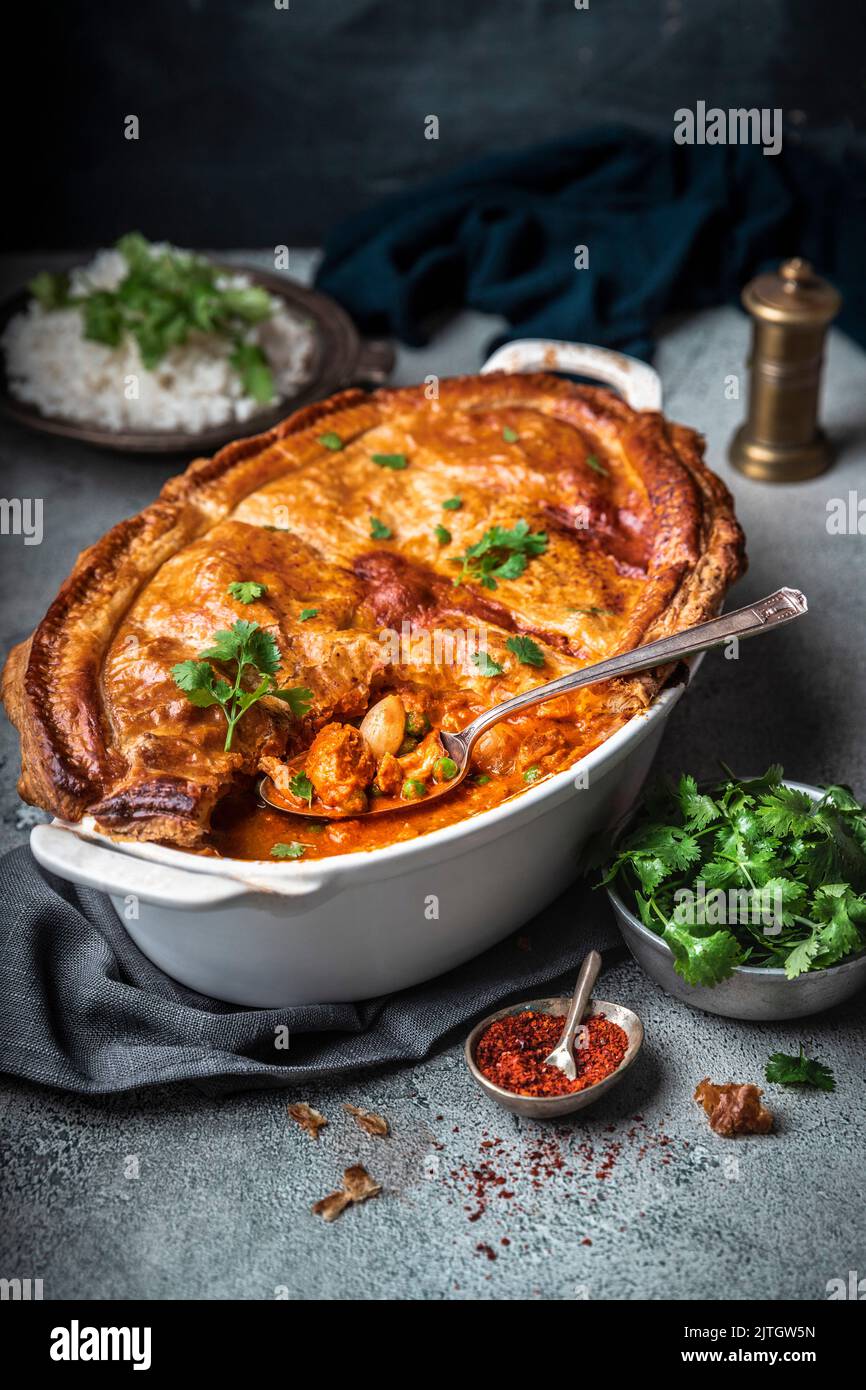 Chicken pot pie with dark pie crust in serving dish, spoon with pie ...
