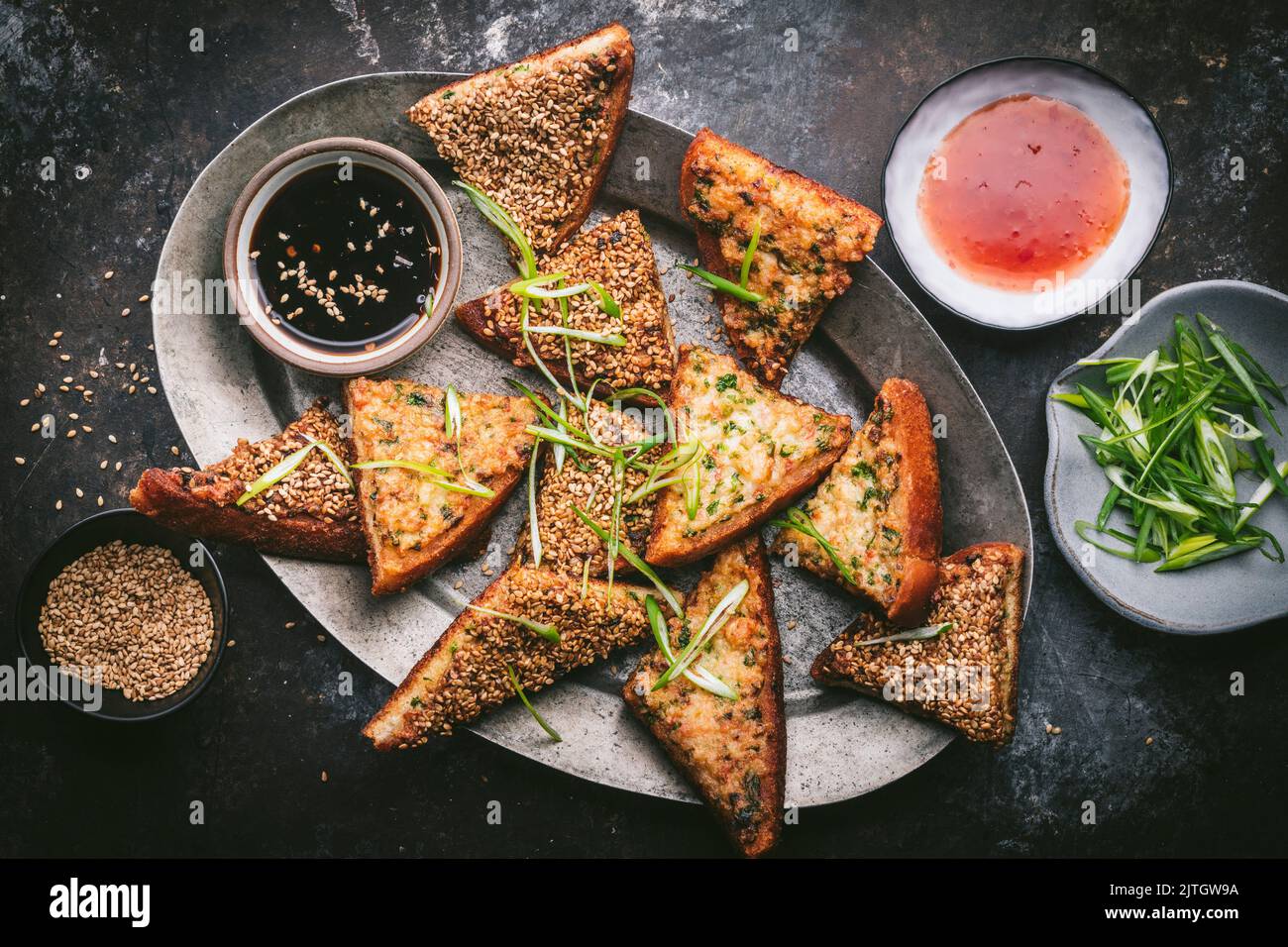 Crispy fried Shrimp Toast triangles on oval metal plate with bowls of ...
