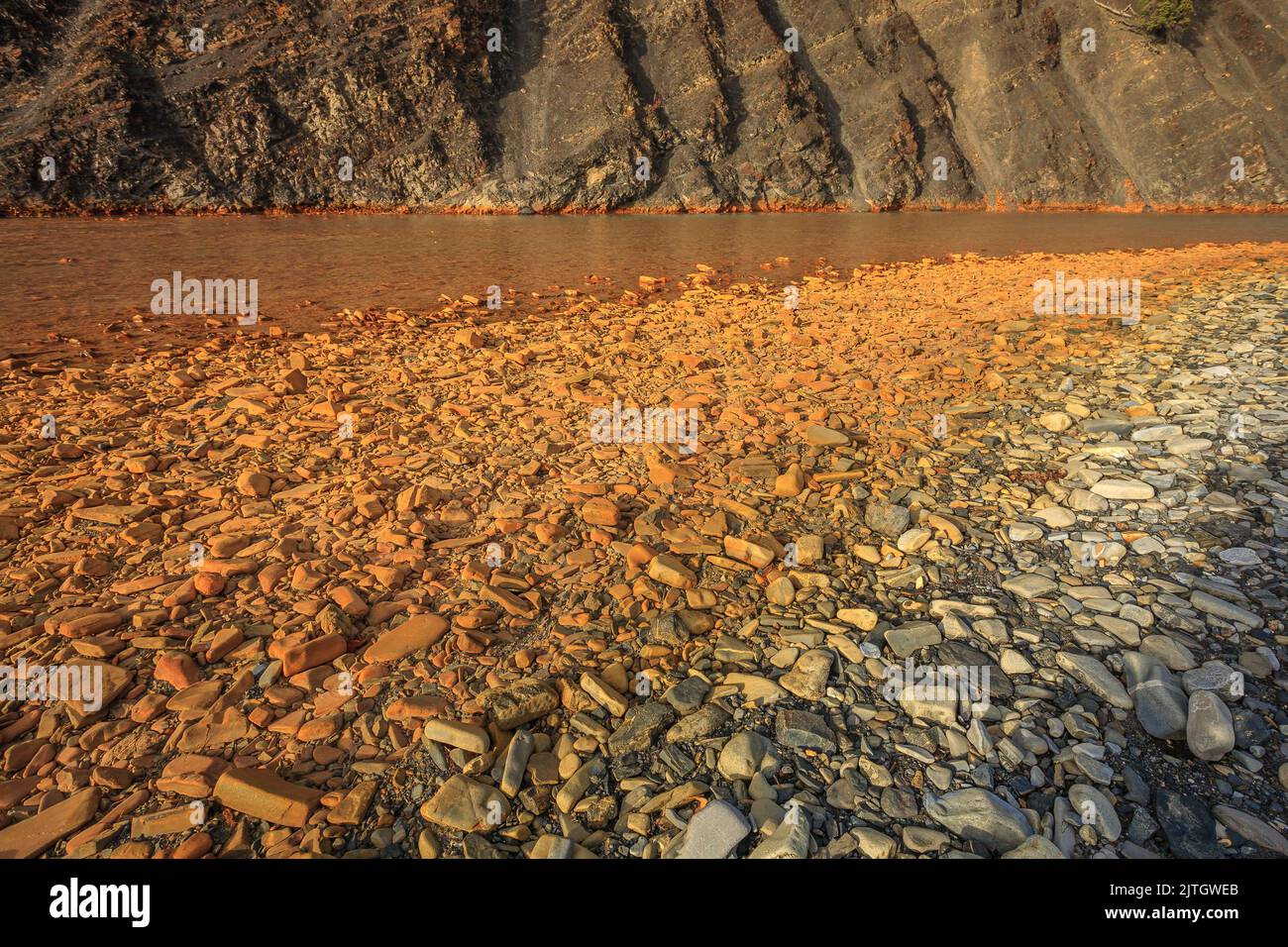 Rocks along the riverbank are stained by dissolved iron and other ...