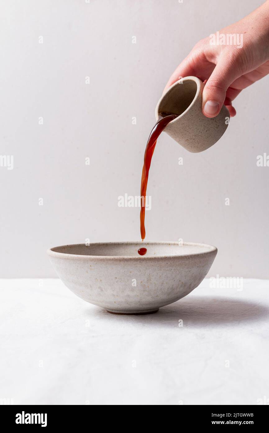 Hand pouring jug of coffee into a ceramic bowl Stock Photo - Alamy