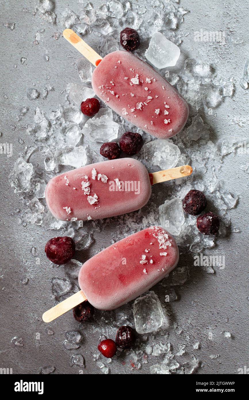Three cherry flavoured popsicles (ice lollies) on crushed ice with ...