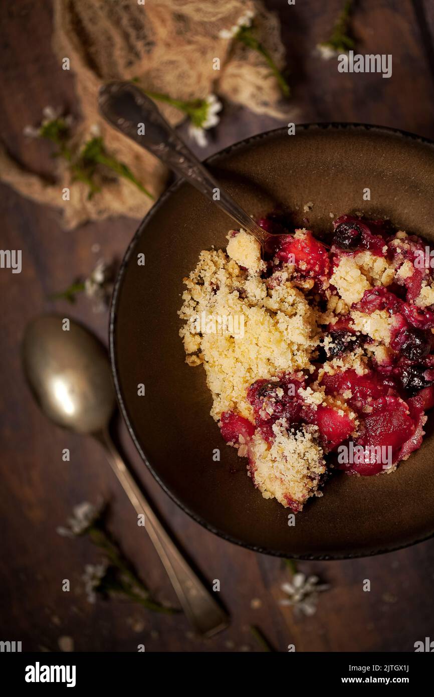 A bowl of apple and blackcurrant crumble in a dark setting Stock Photo ...