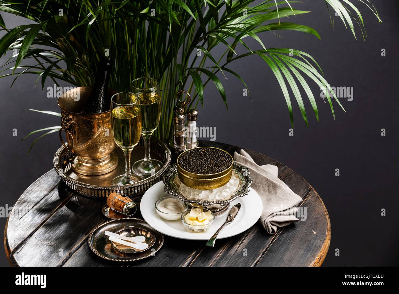 Black caviar on ice in silver bowl and Champagne in ice bucket on dark ...