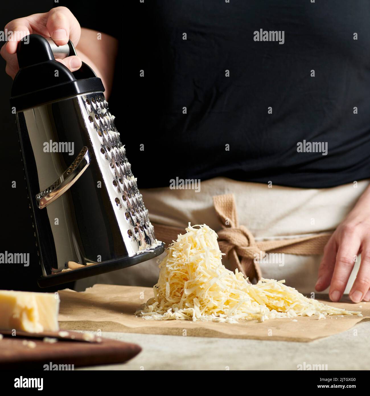 Hands grating cheese onto parchment paper Stock Photo - Alamy