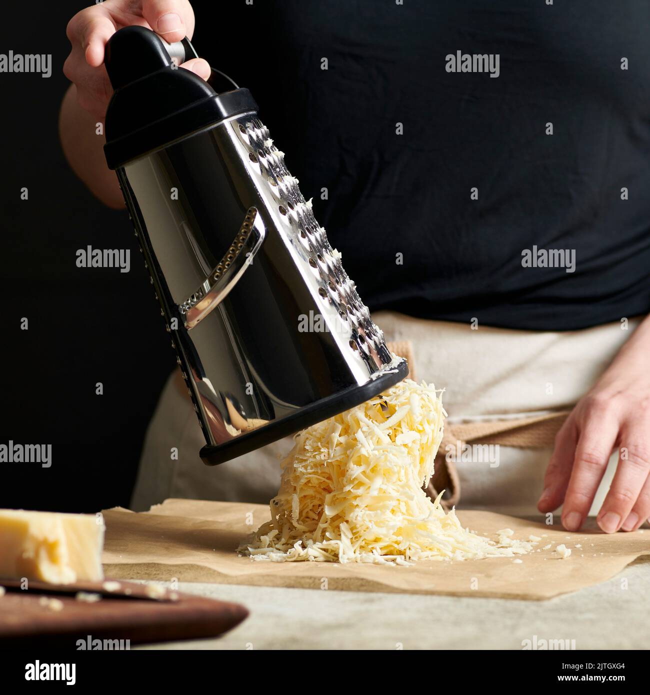Hands grating cheese onto parchment paper Stock Photo - Alamy