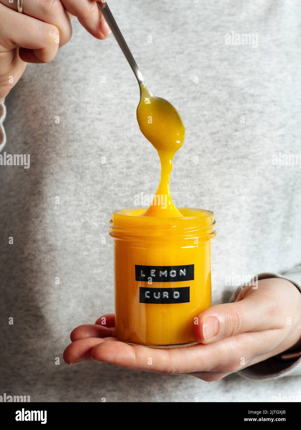 Delicious homemade lemon curd. Glass jar with lemon curd and full spoon ...