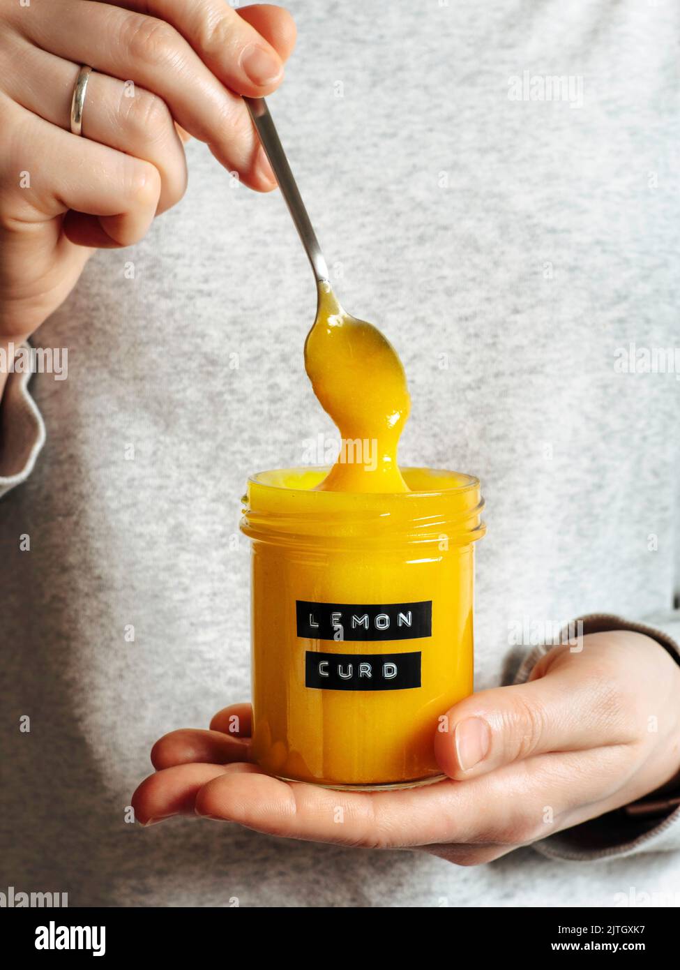 Delicious homemade lemon curd. Glass jar with lemon curd and full spoon ...