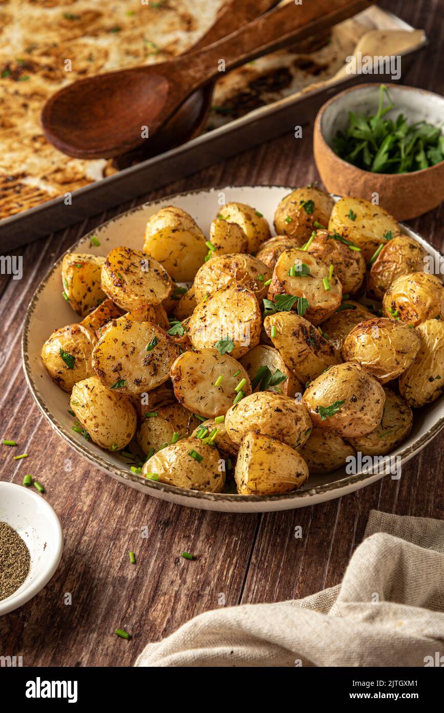 Bowl of baked herb potatoes with wood spoons Stock Photo - Alamy