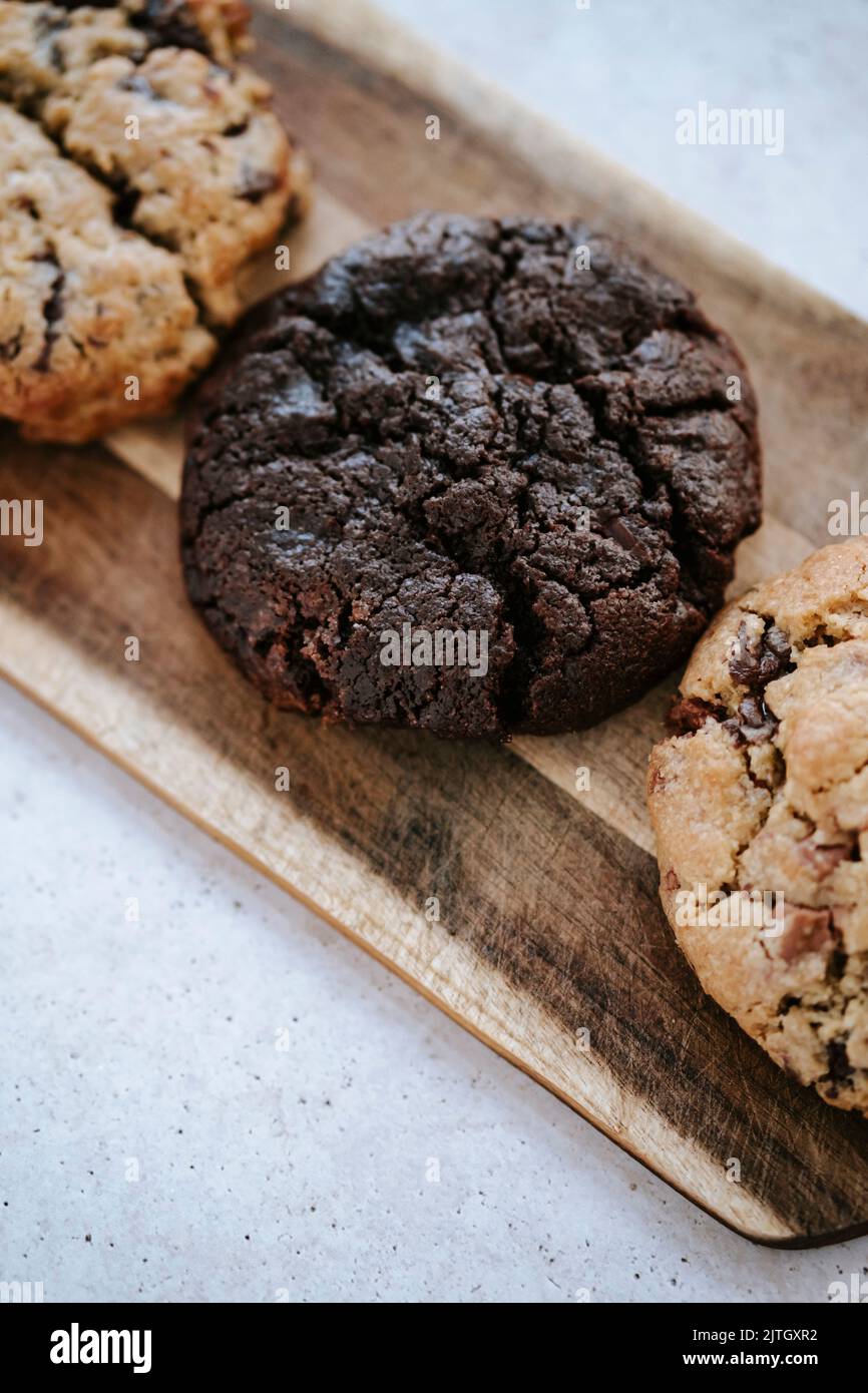 variety of 3 cookies, placed on a wooden plate, on a grey background ...
