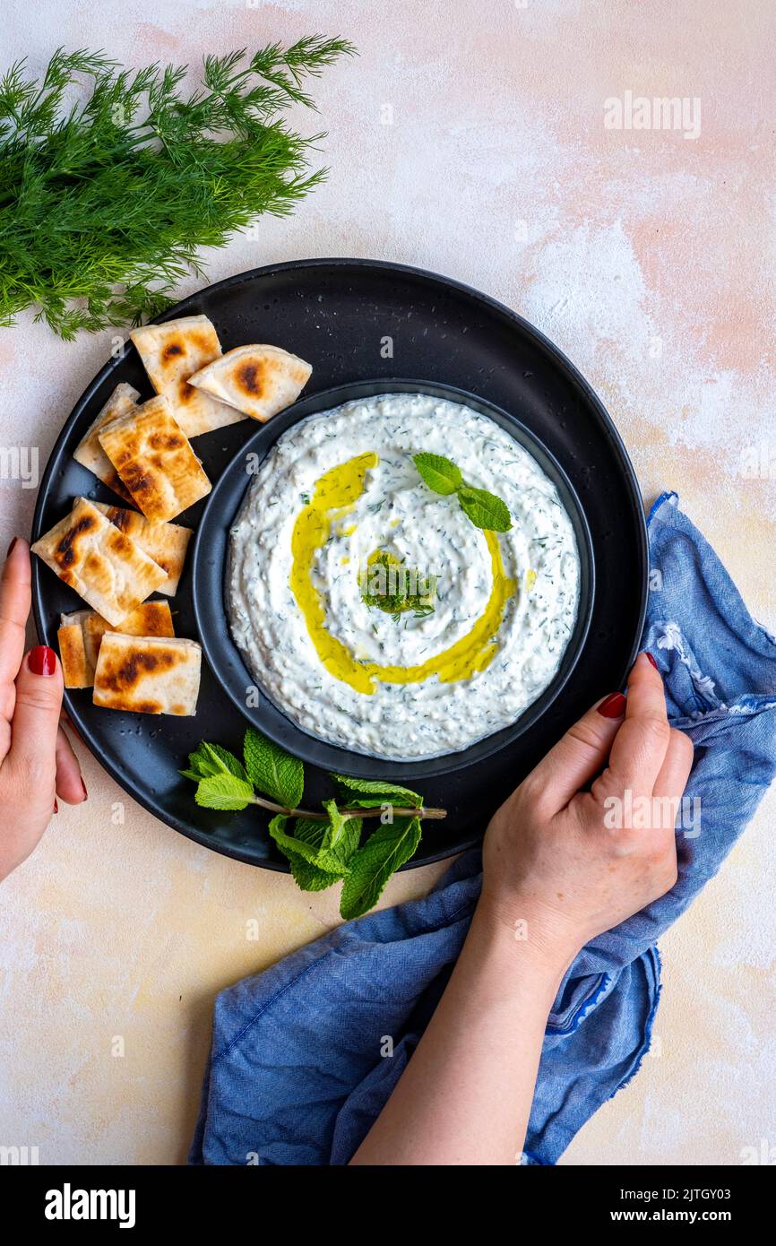Woman holding Turkish haydari meze dip topped with fresh mint leaves ...