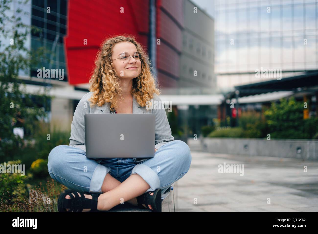 Positive girl with curly hair in eyeglasses working remotely with ...