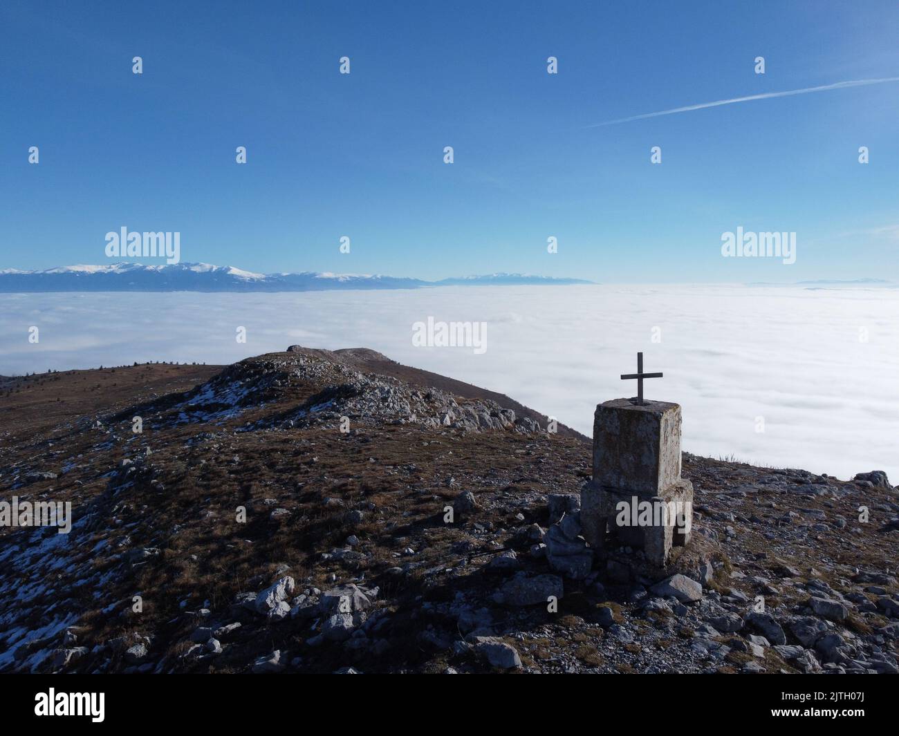 A small grave with a cross on a high hill by the blue sea with shiny ...
