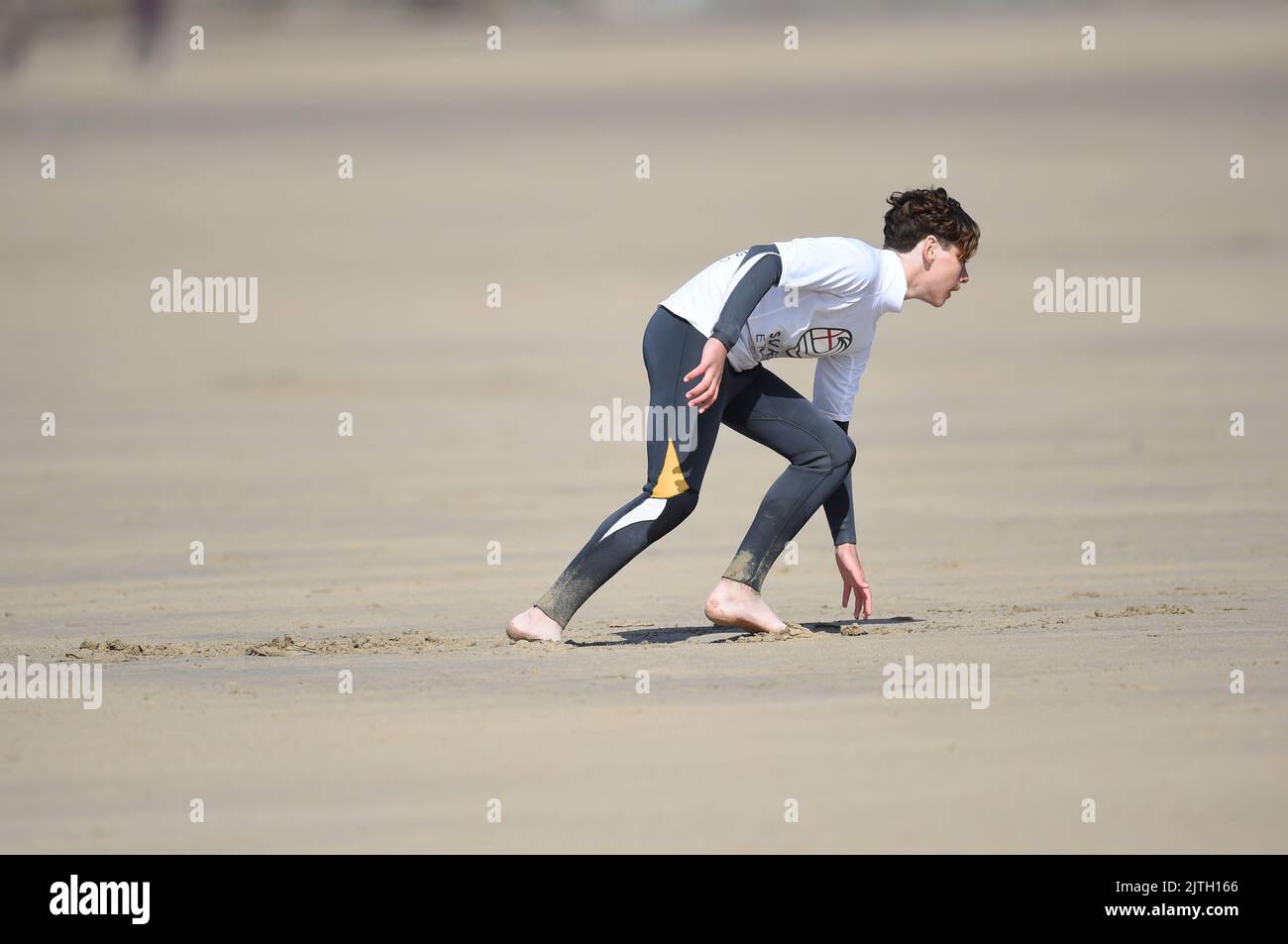 Surfer doing warm up exercises on beach before event Stock Photo - Alamy