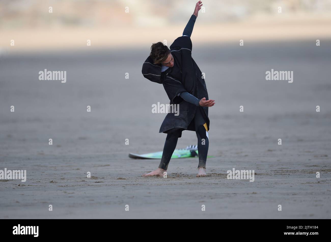 Surfer doing warm up exercises on beach before event Stock Photo - Alamy