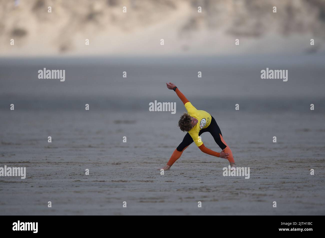Surfer doing warm up exercises on beach before event Stock Photo - Alamy