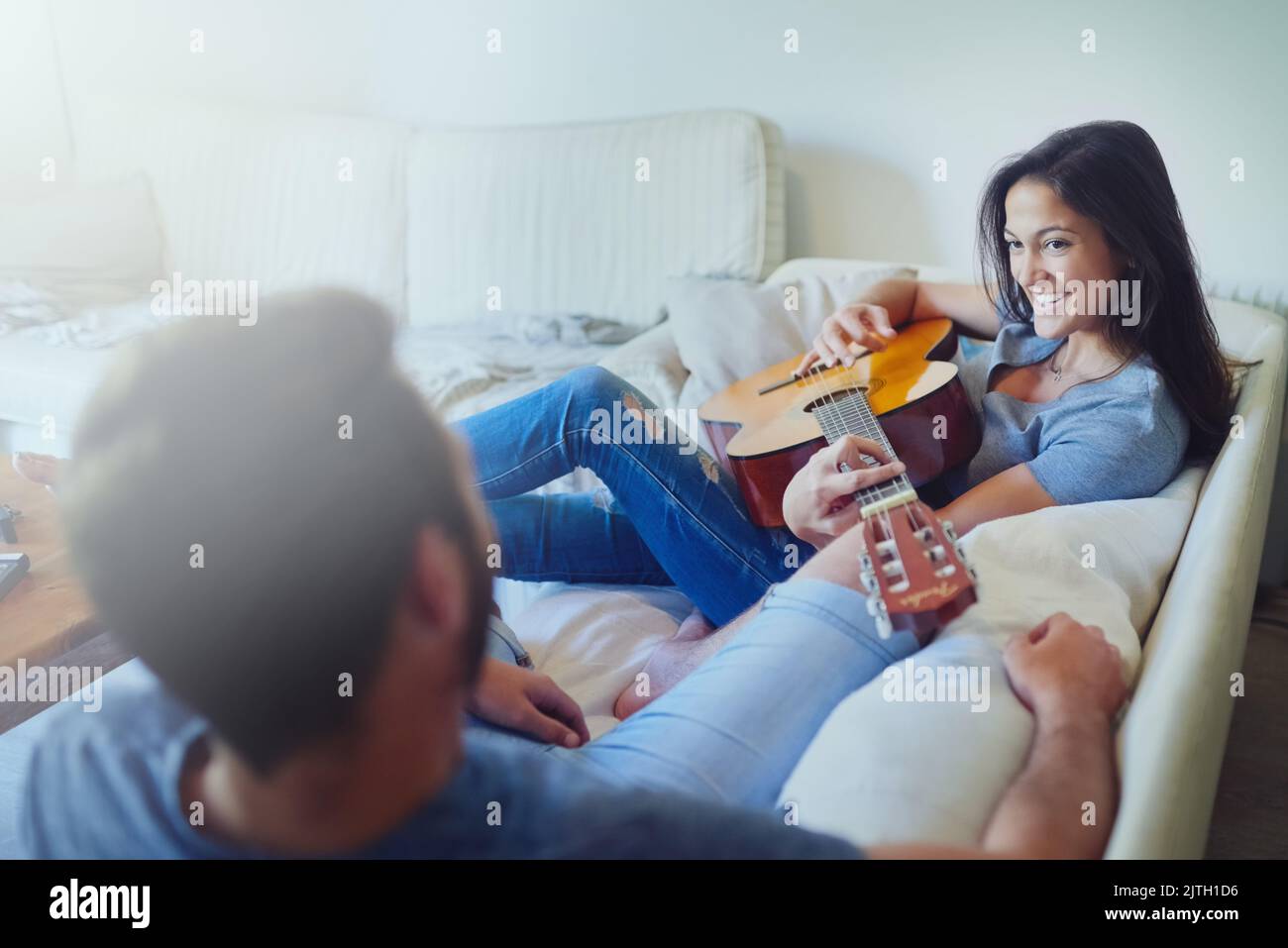 Serenading him with a song. a young woman playing guitar for her ...