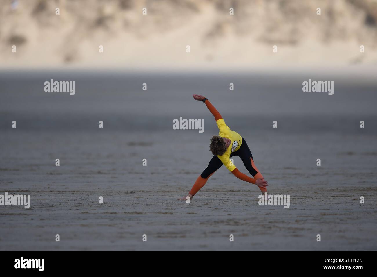 Surfer doing warm up exercises on beach before event Stock Photo - Alamy