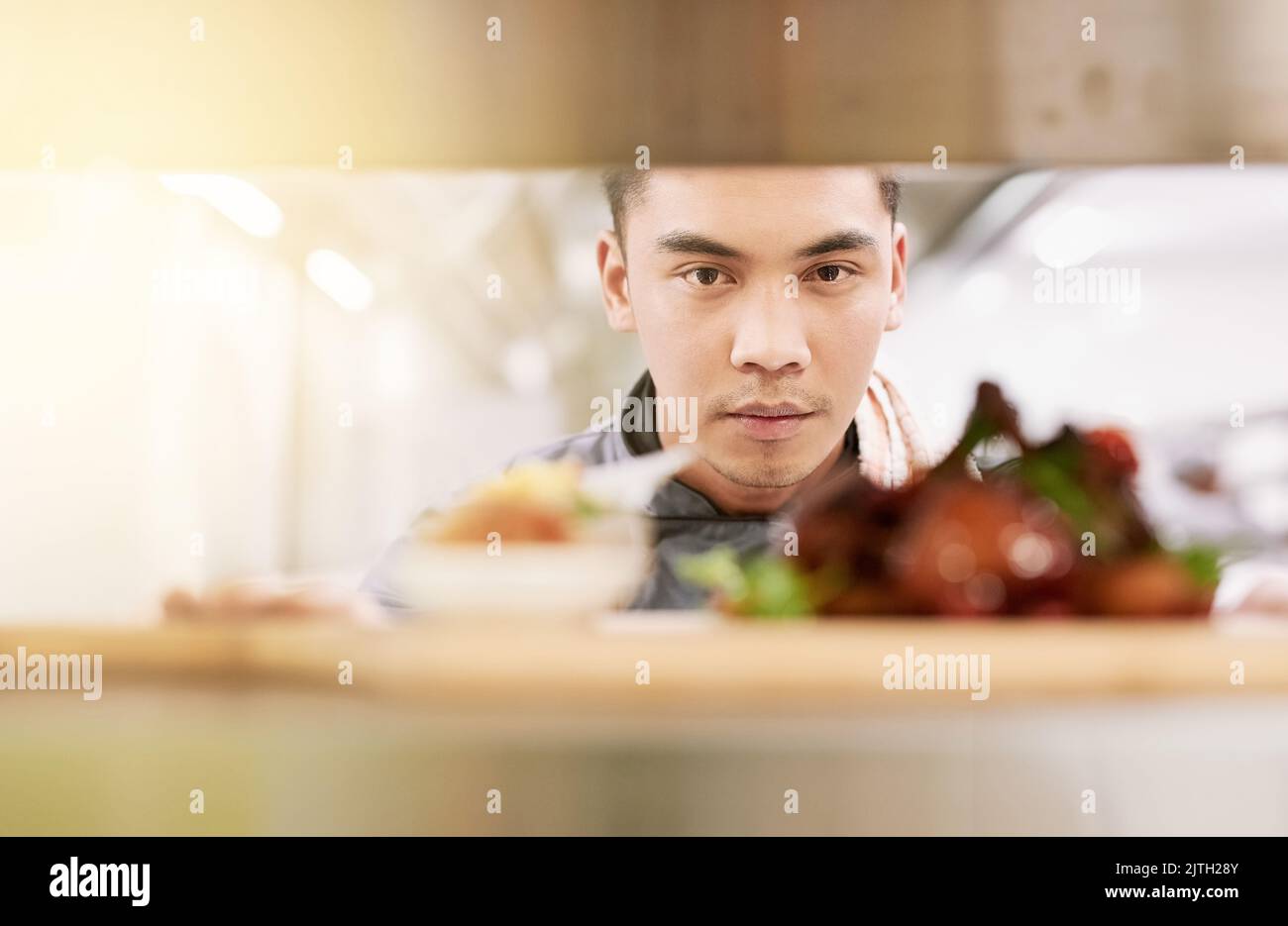 Order up. Cropped portrait of a young male chef cooking in his kitchen ...