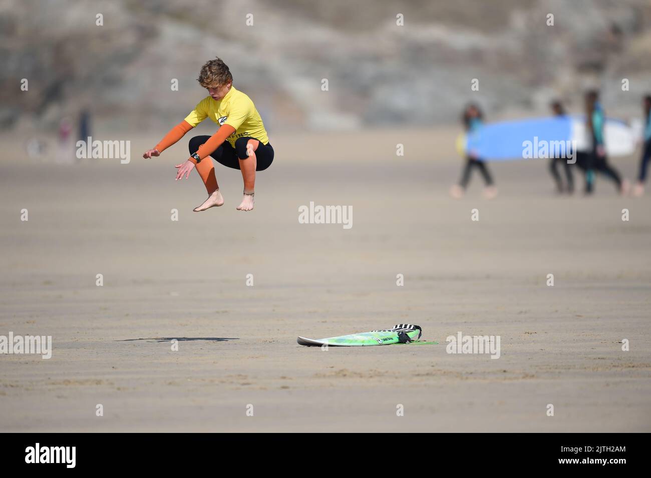 Surfer jumping in the air doing warm up exercises on beach before event ...