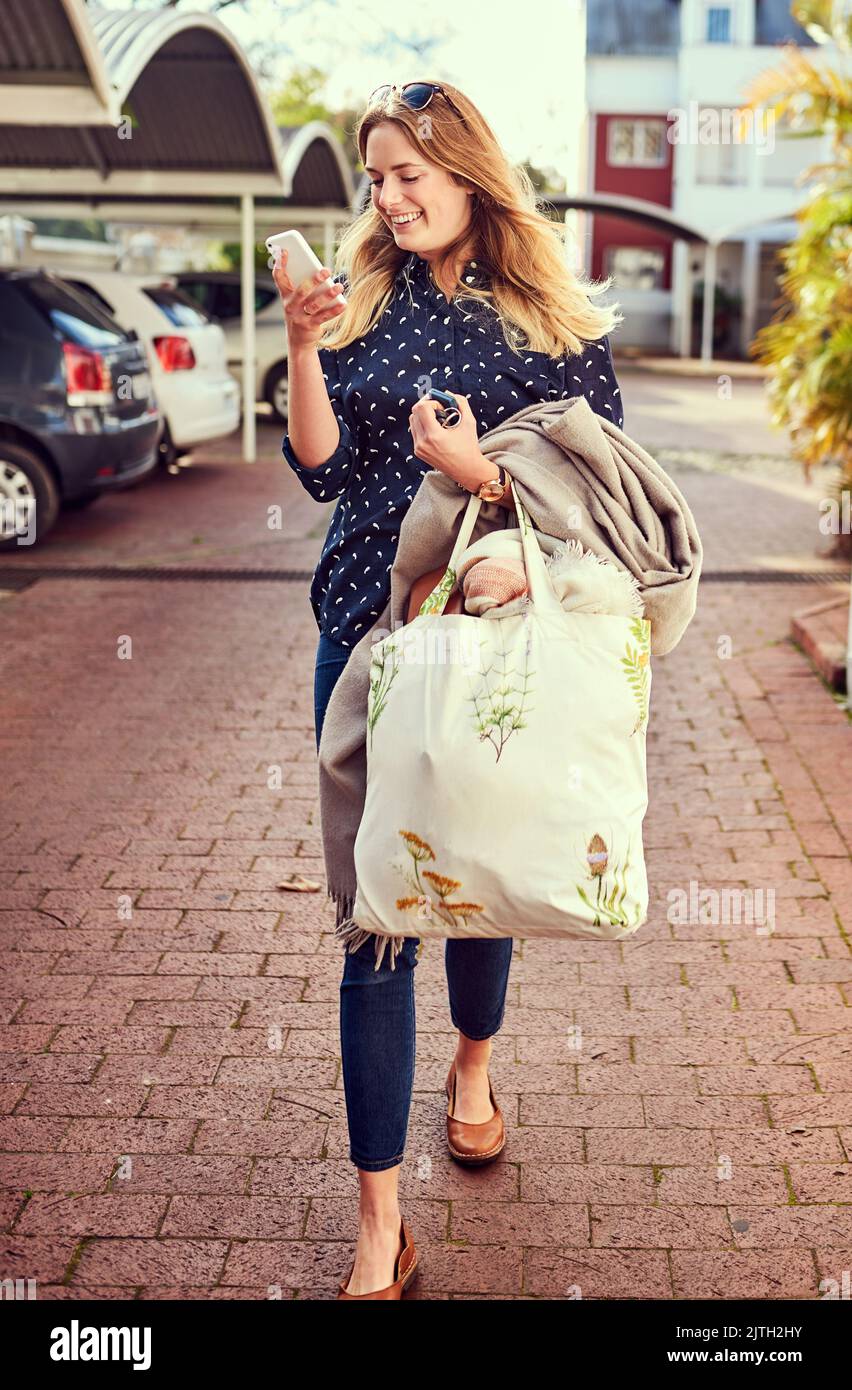 Out and about running her errands. an attractive young woman texting on ...