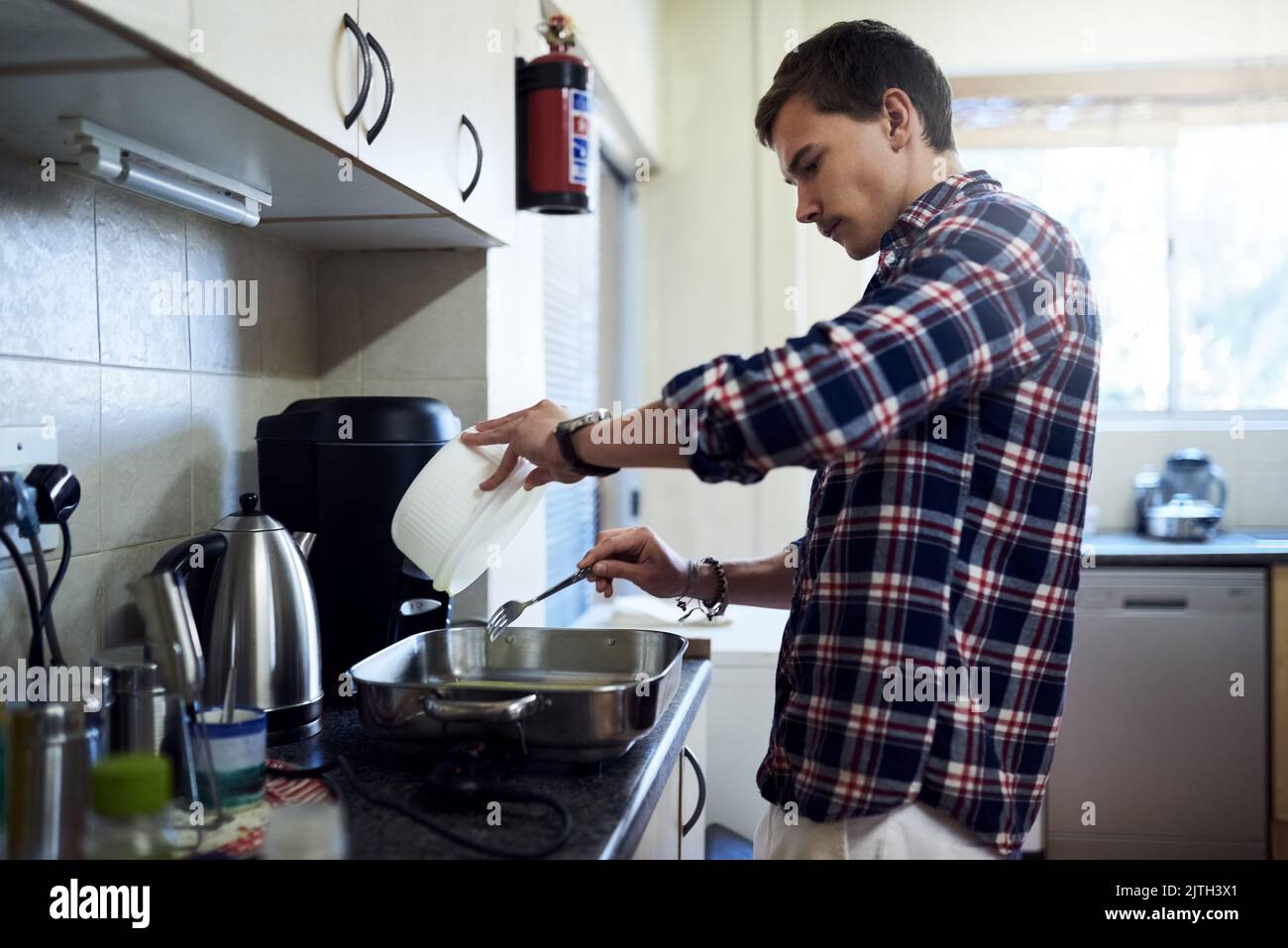 Cooking up something in the kitchen. a handsome young man cooking in ...