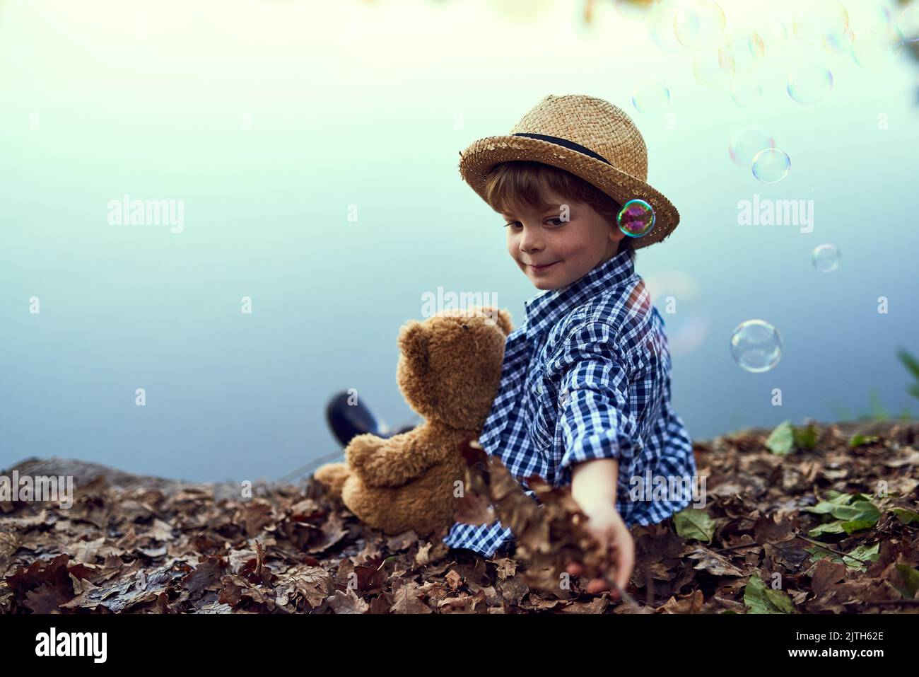 Just him and his teddy in the great outdoors. a little boy sitting in ...