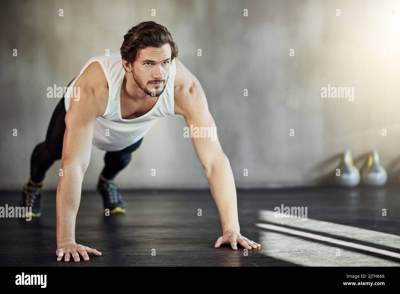 Getting stronger with every lift. a handsome young man doing pushups as ...