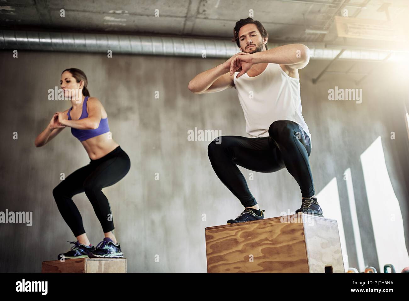 Push yourself, its so worth it. two young people box jumping as part of ...