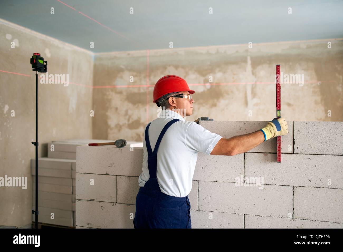 Bricklayer using spirit bubble and laser level to precise check ...